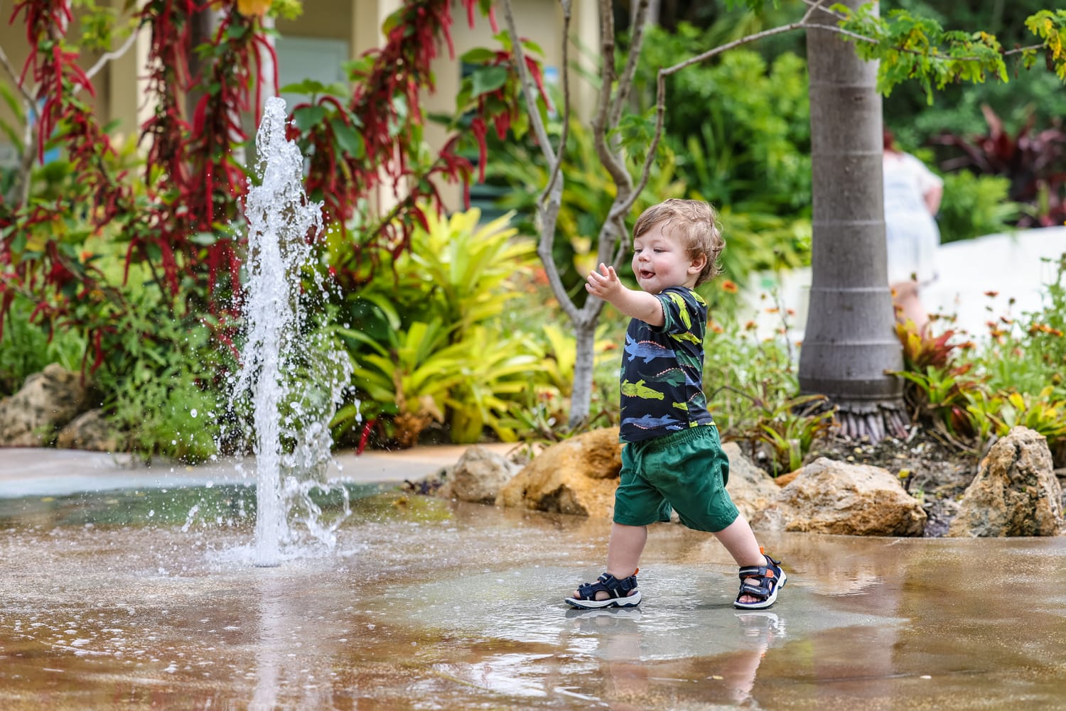 A toddler playing with a water fountain