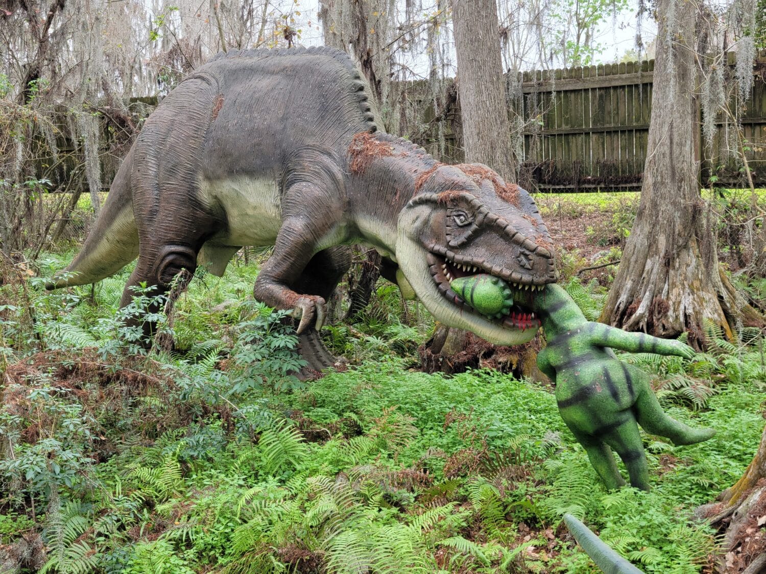 A  dinosaur statue in the woods.