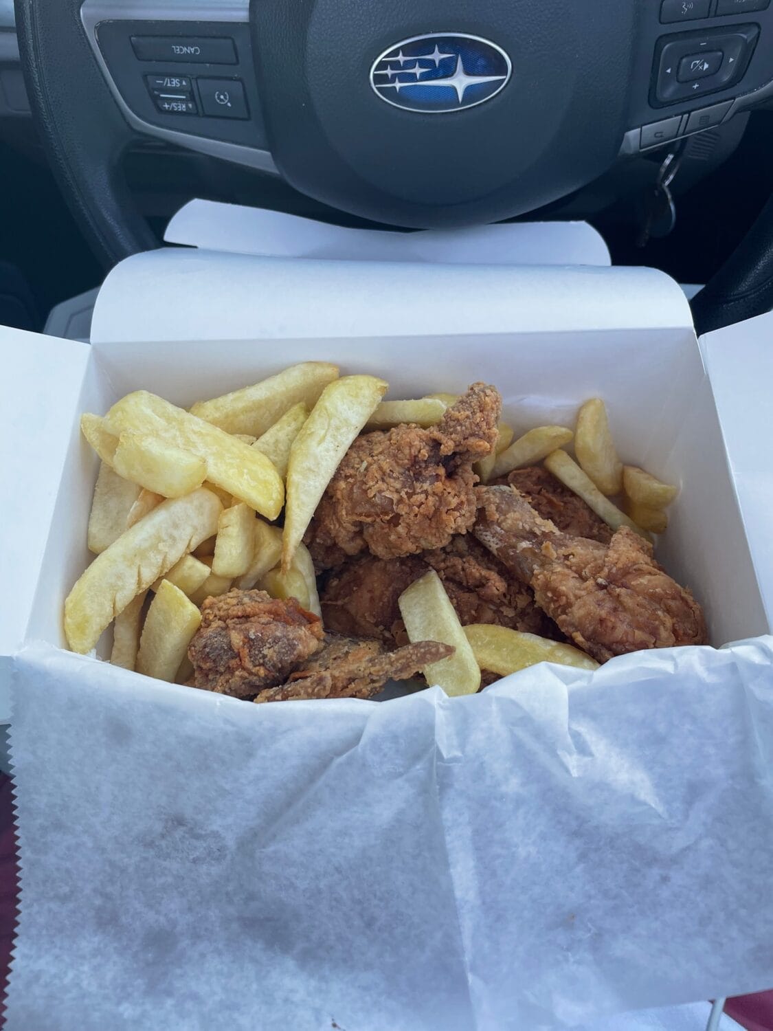 A take out box of delicious chicken and fries.