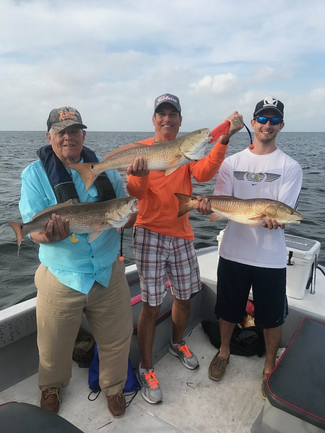 a family displaying their catch of redfish on a boat