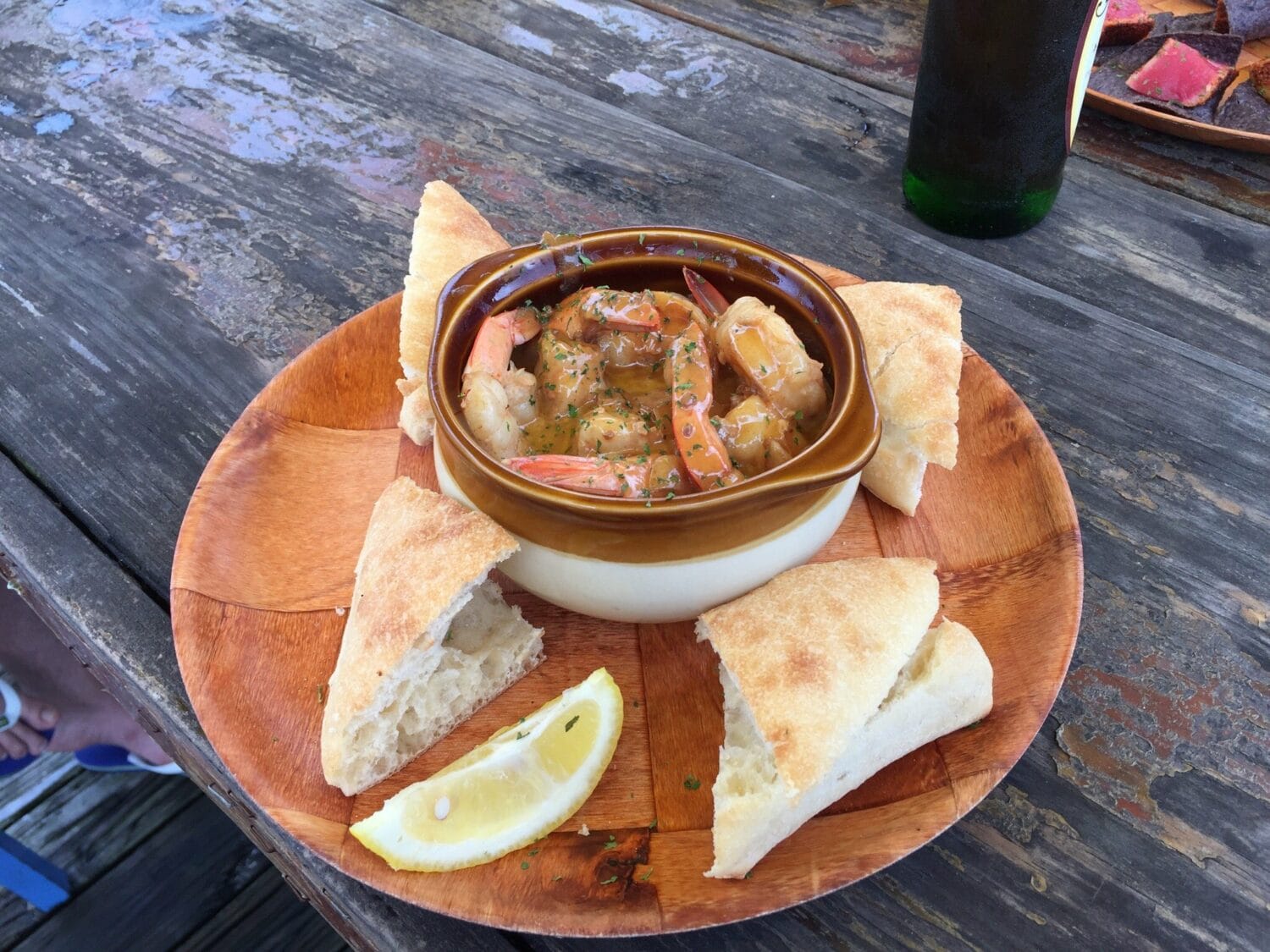 a bowl of shrimp served with chunks of bread on a wooden board ready for a flavorful meal