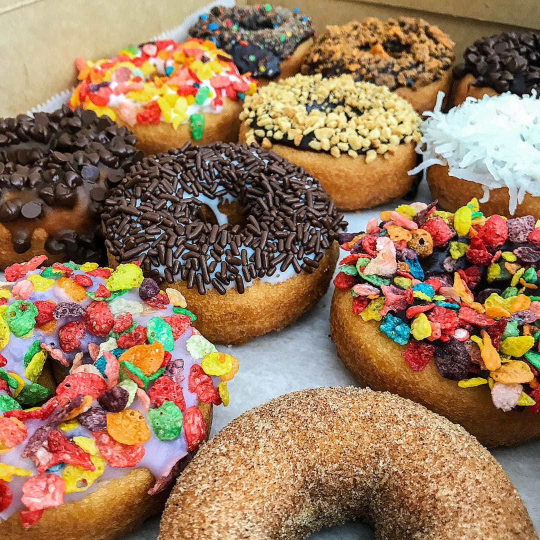 A box of craft donuts with various toppings.
