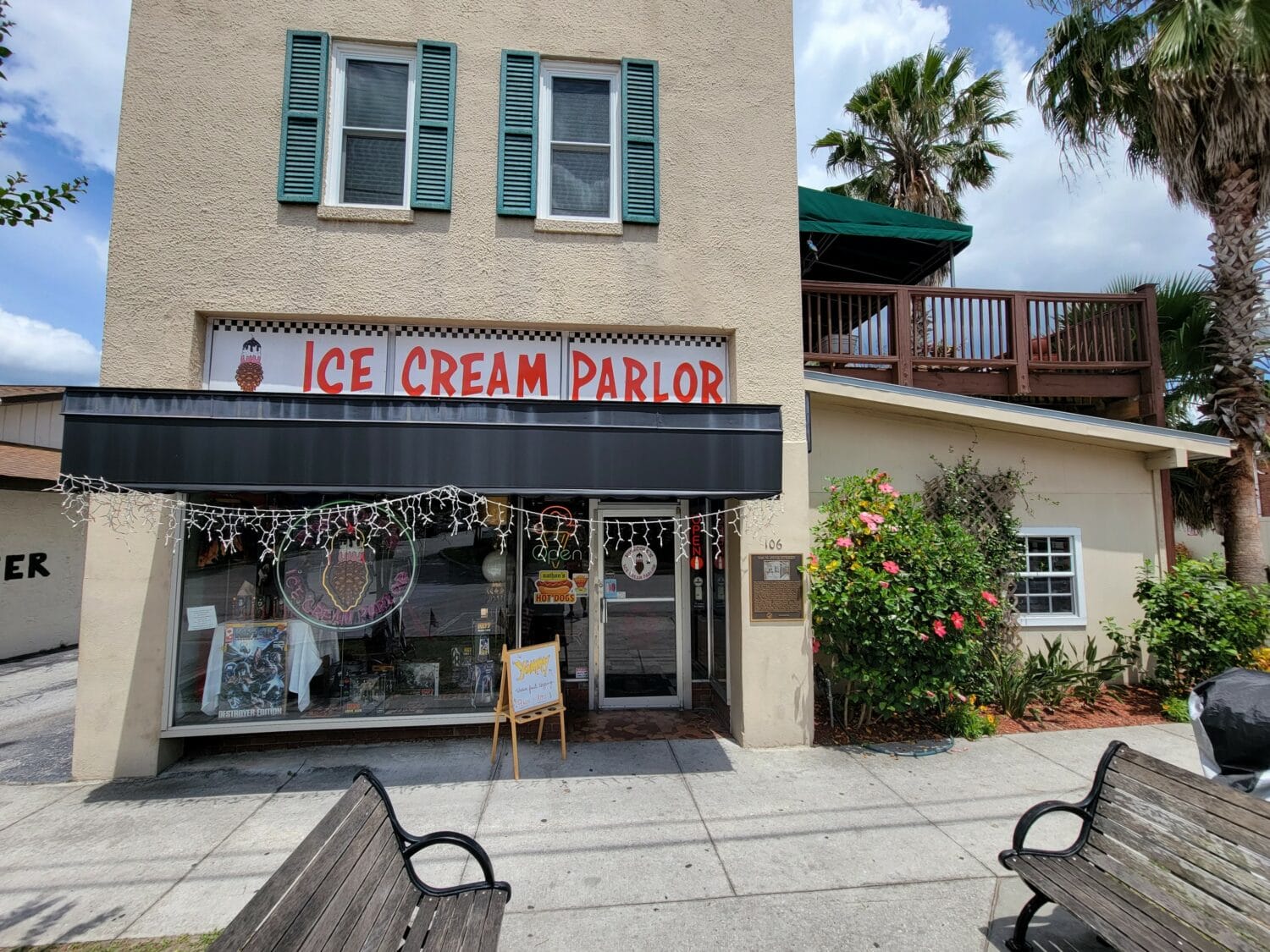 a charming ice cream parlor storefront with green window shutters and a welcoming sign