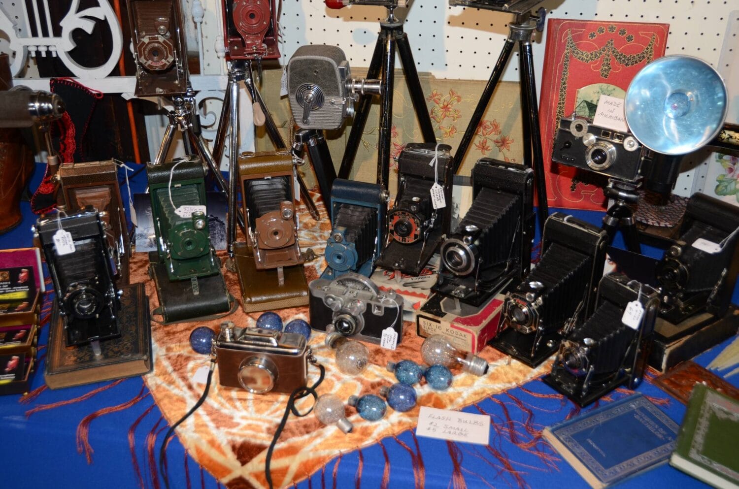 a collection of classic cameras and photography equipment artfully displayed on a patterned tablecloth