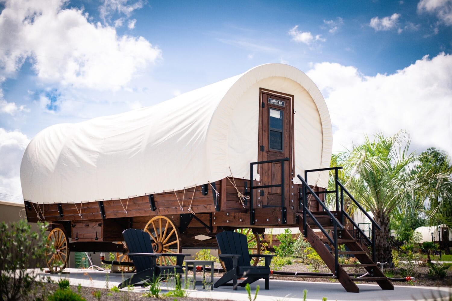 a covered wagon converted into a lodging space with steps and a sitting area outside