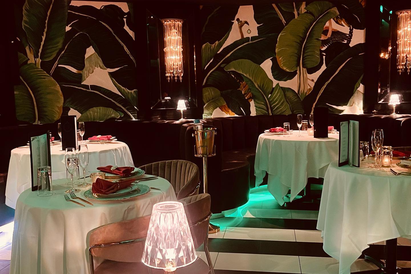 a cozy and inviting dining setting with tropical wallpaper plush seating and elegant table settings illuminated by warm intimate lighting