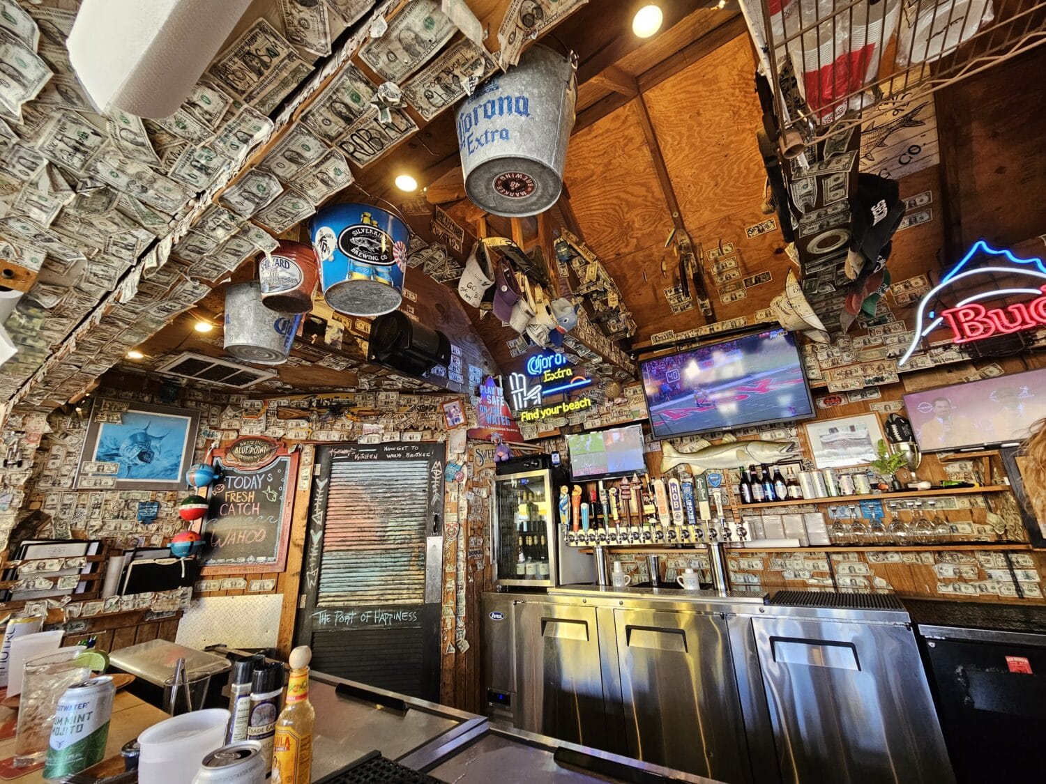 a cozy bar interior with walls and ceiling covered in dollar bills and eclectic decor showcasing a vibrant atmosphere