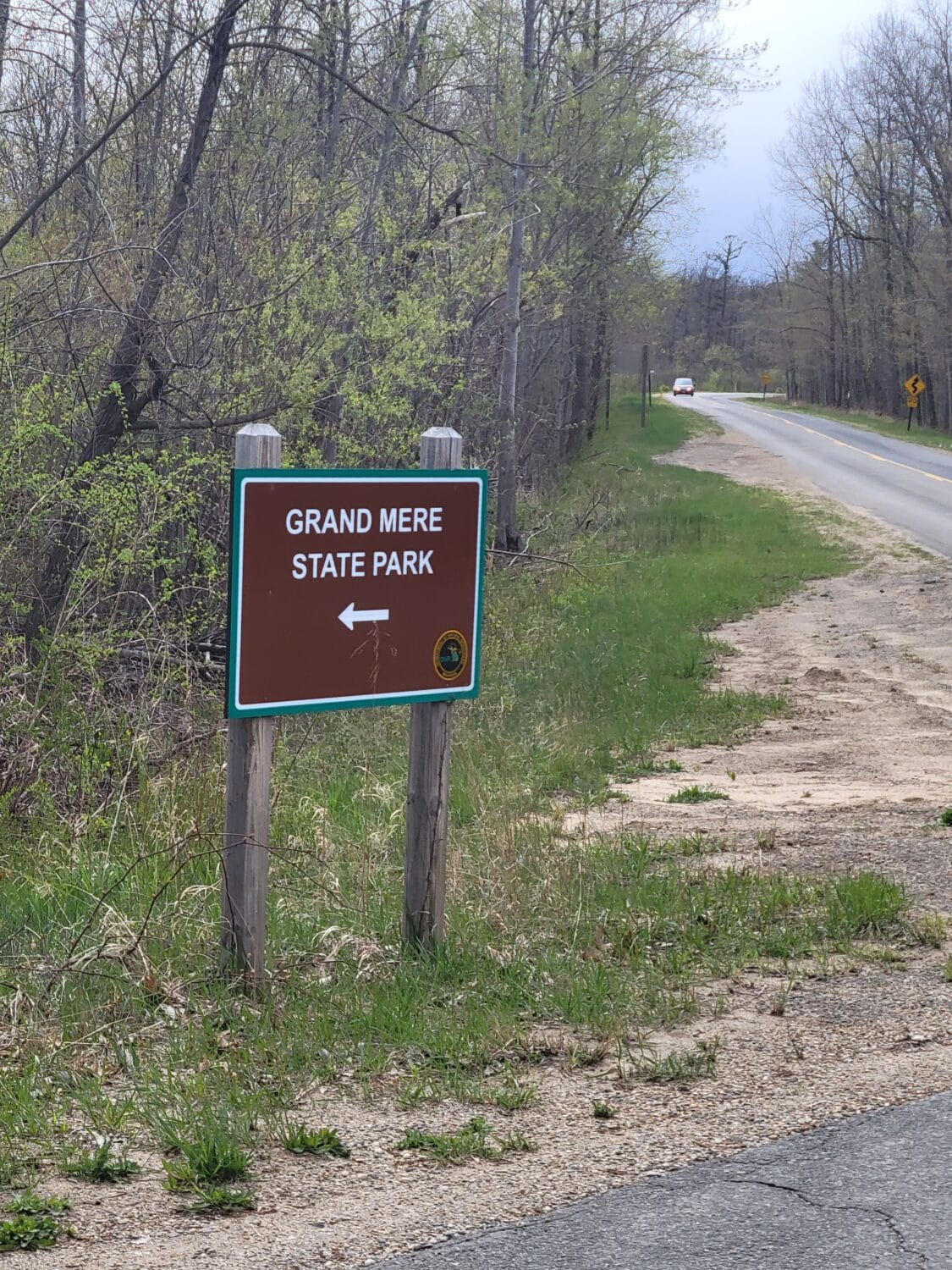a directional sign for grand mere state park positioned along a country road indicating adventure is just a turn away