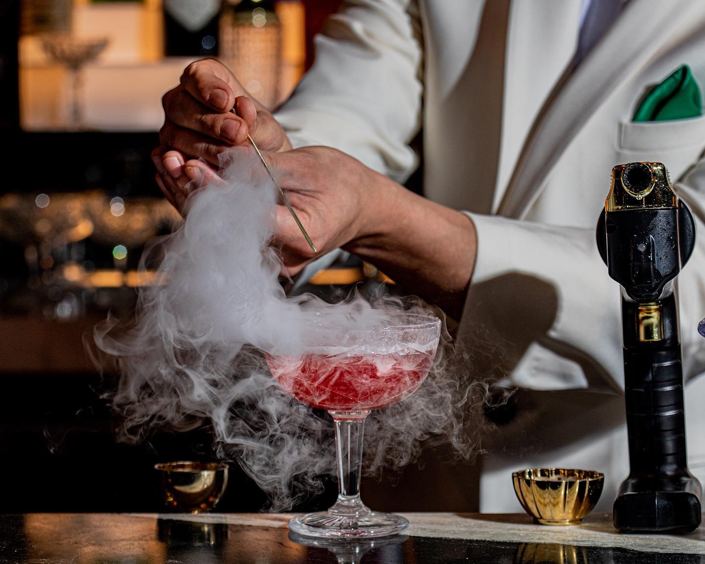 a dramatic cocktail presentation with cascading smoke adding a theatrical effect to the red drink on the bar