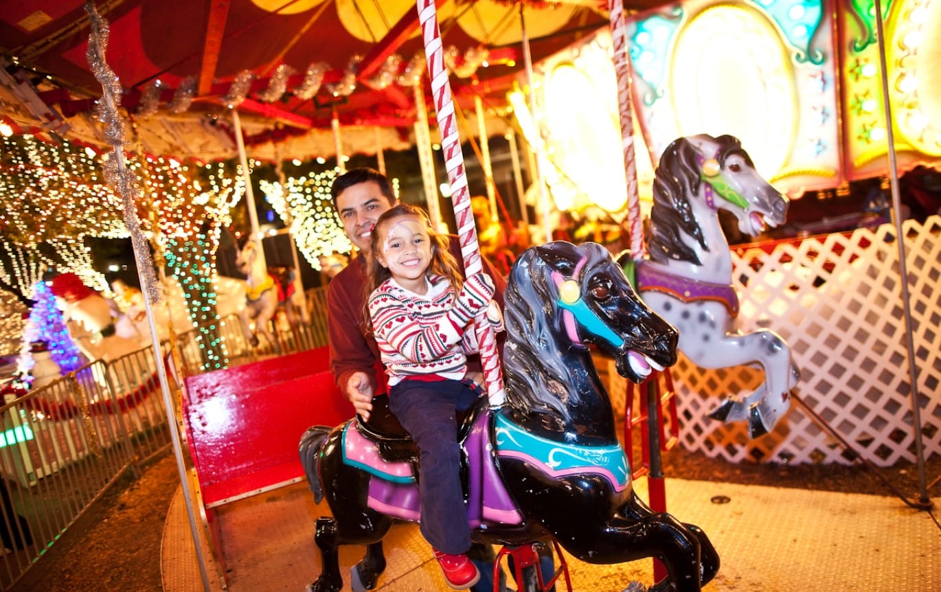 a father and daughter enjoying the carousel at the park