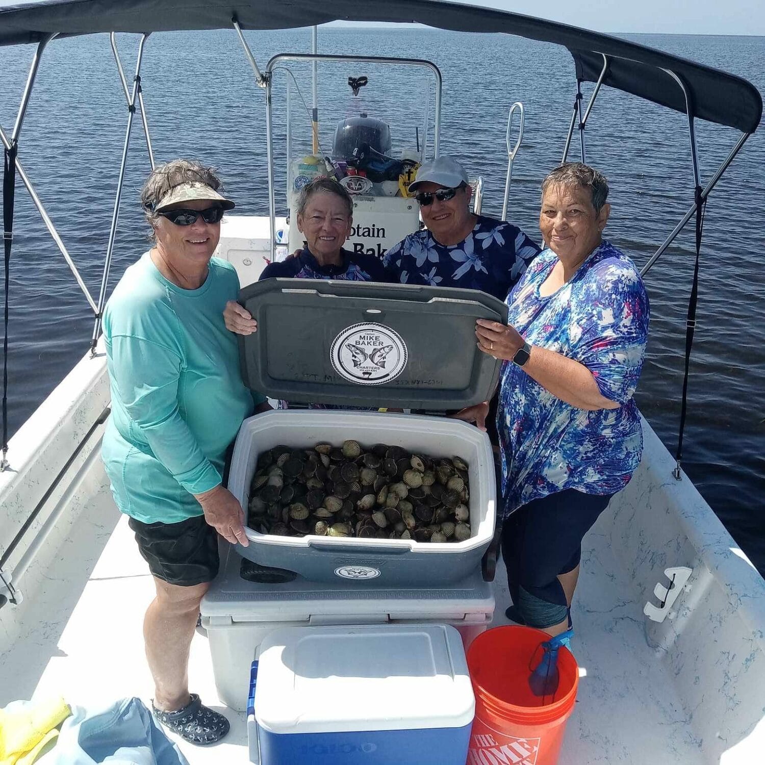 a group of people on a boat proudly showing a cooler full of harvested scallops from a day at sea