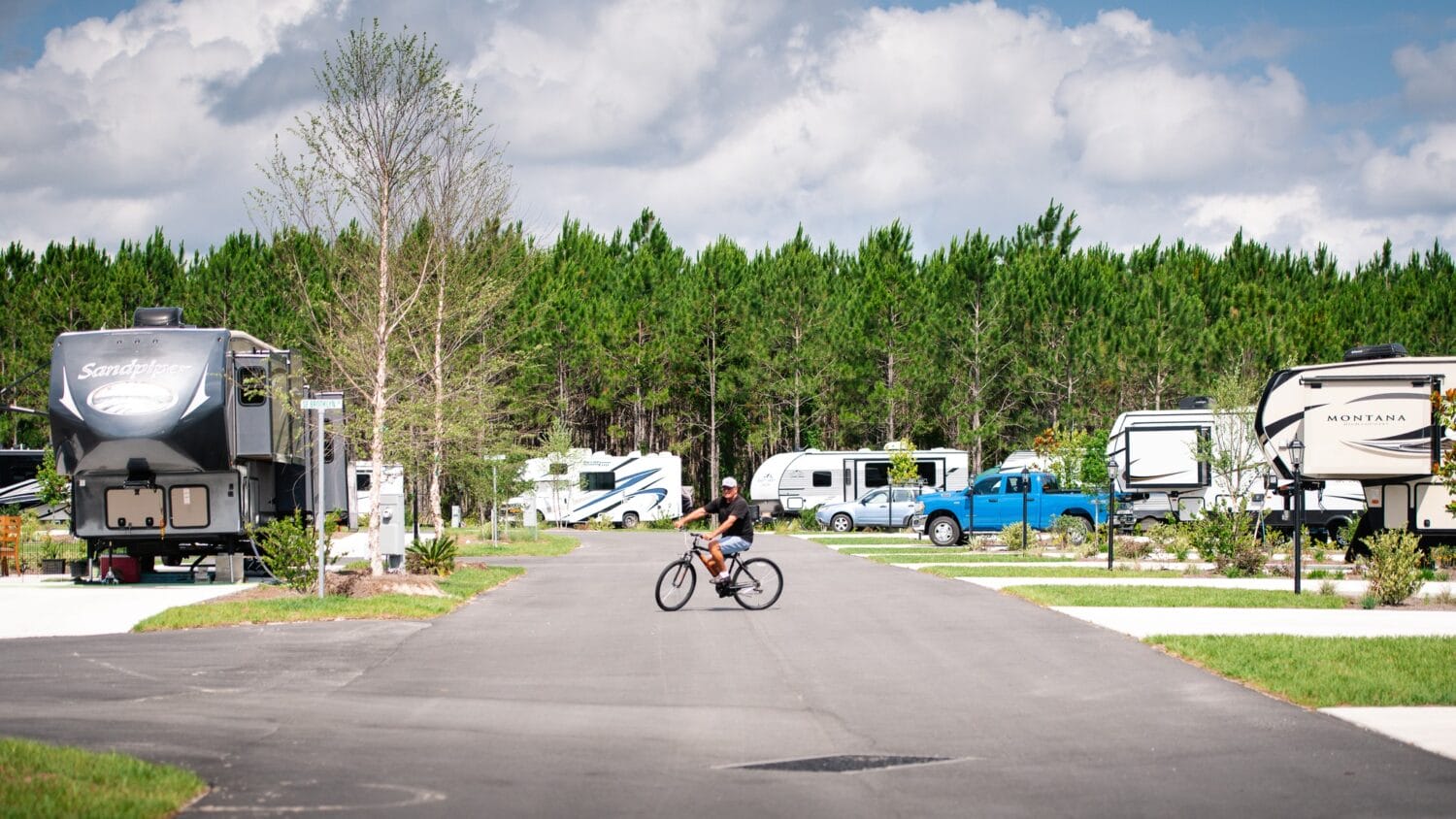 a man cycling on a road at keystone heights rv resort with rvs parked on either side