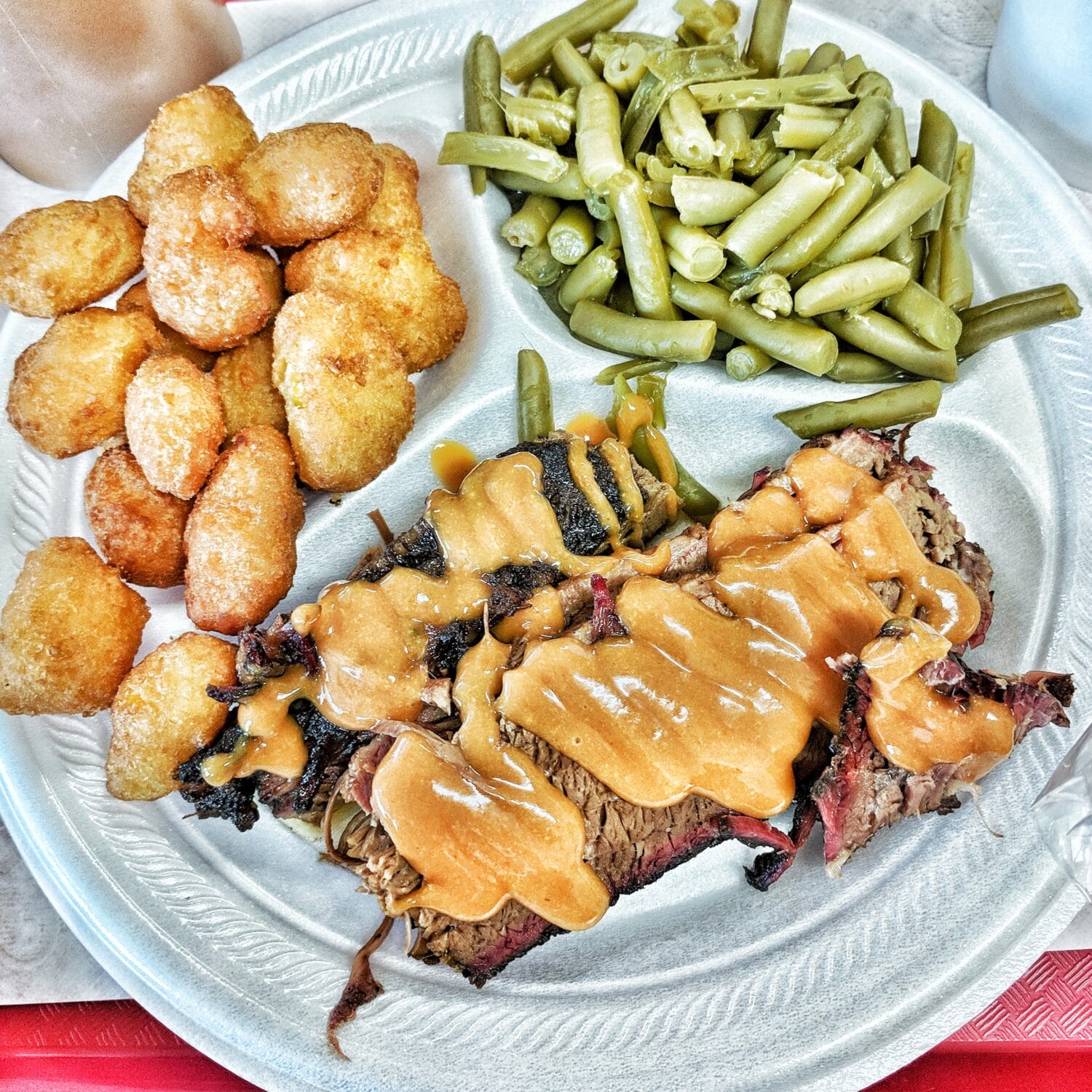 a plate of barbecue topped with savory sauce with sides
