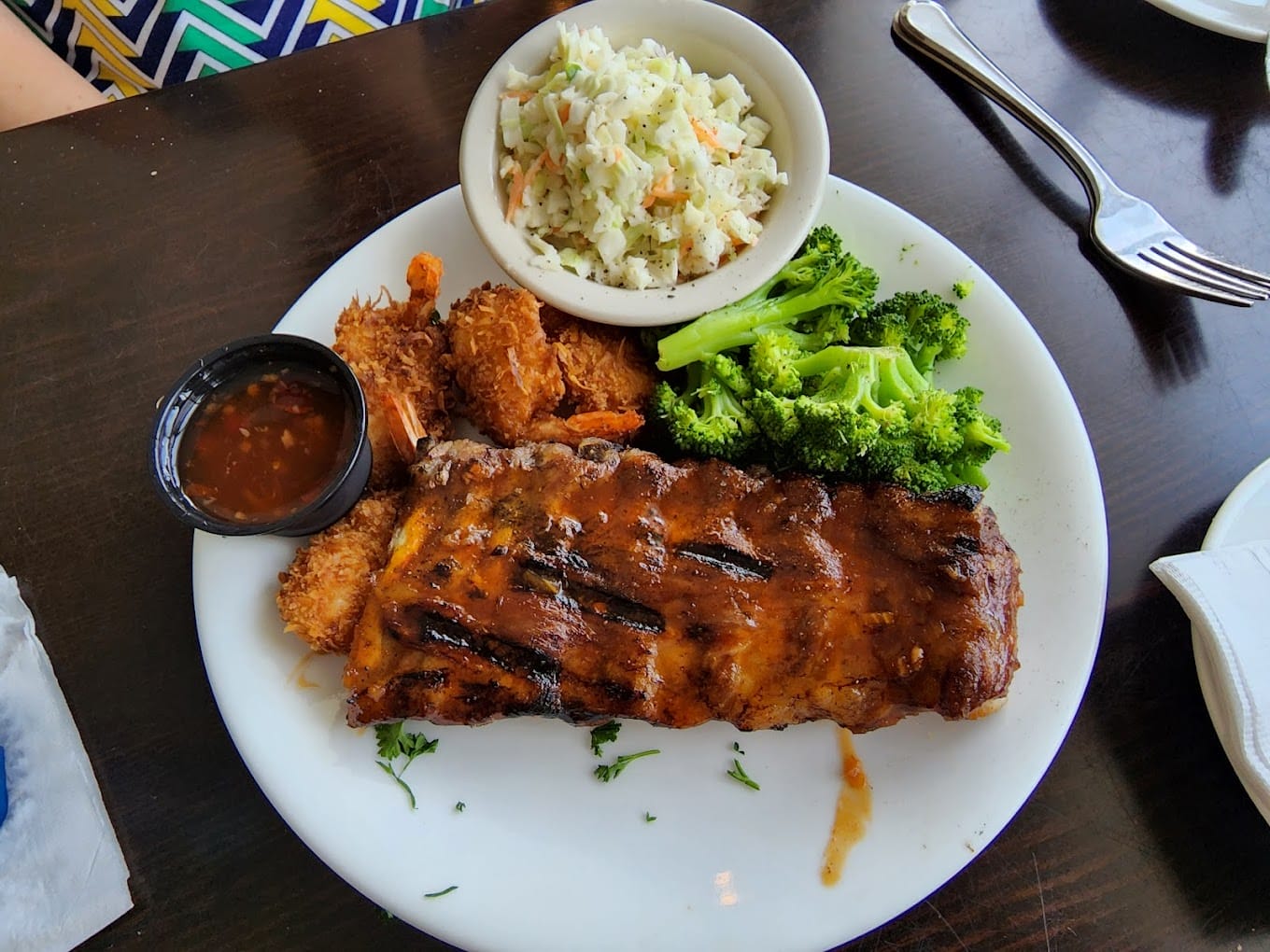 a plate with bbq ribs coleslaw and coconut shrimp served with broccoli