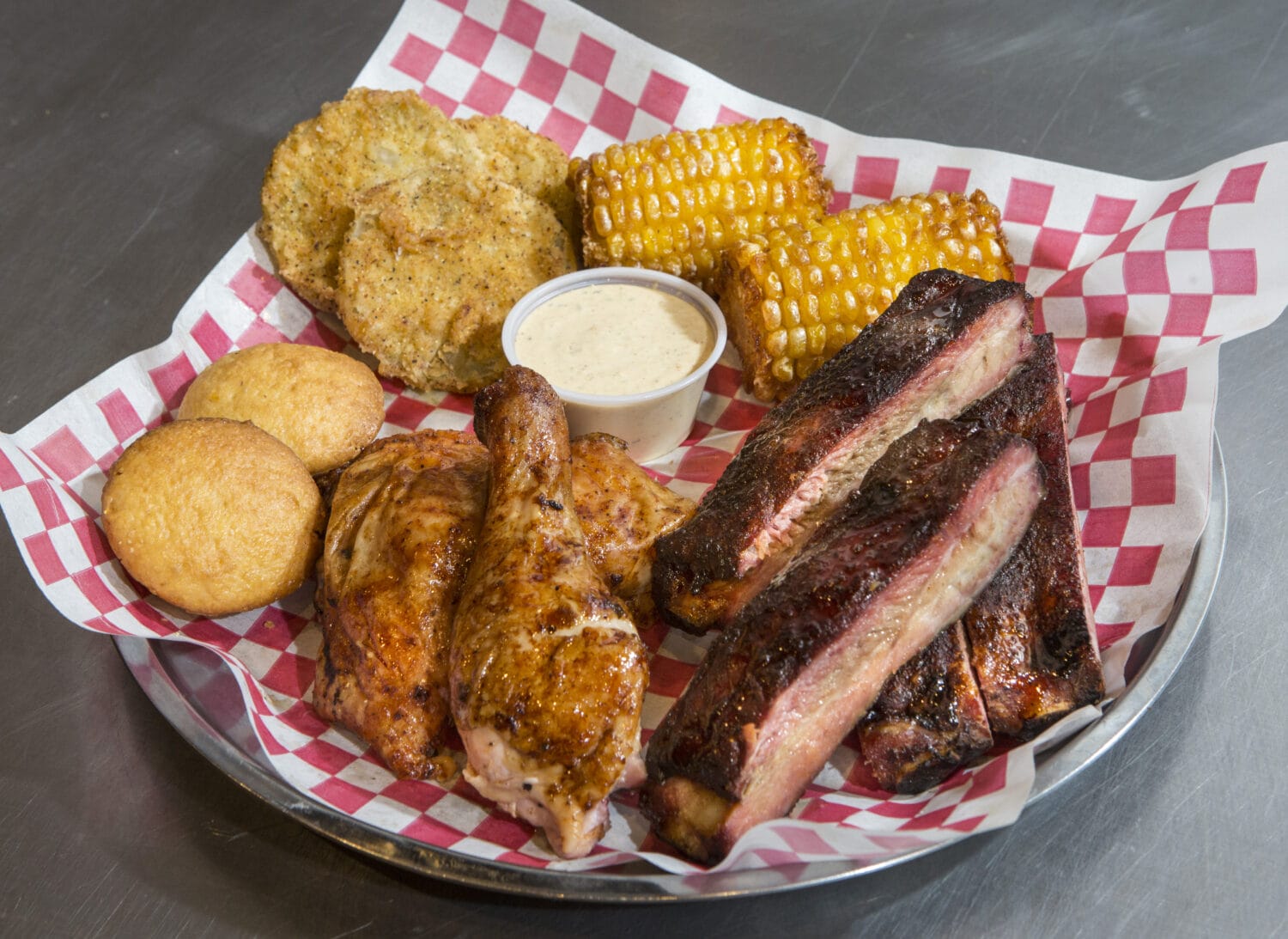 a plate with juicy barbecue chicken and pork barbecue and various sides
