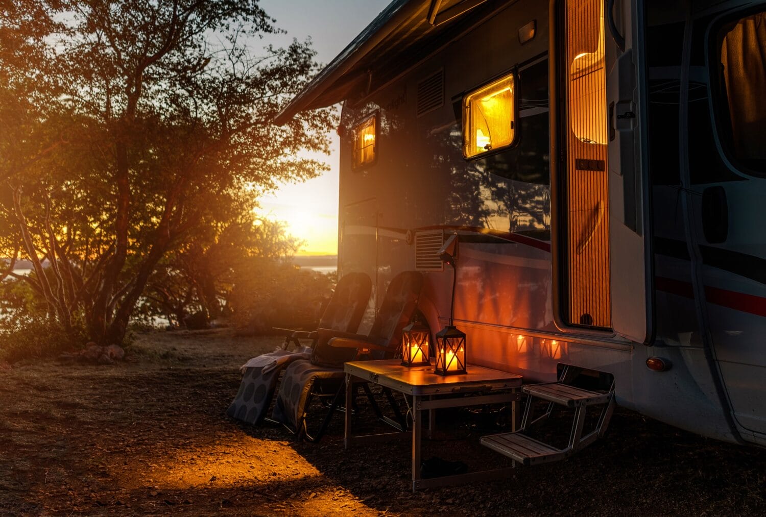 a serene sunset view with glowing lanterns outside an rv at a campsite