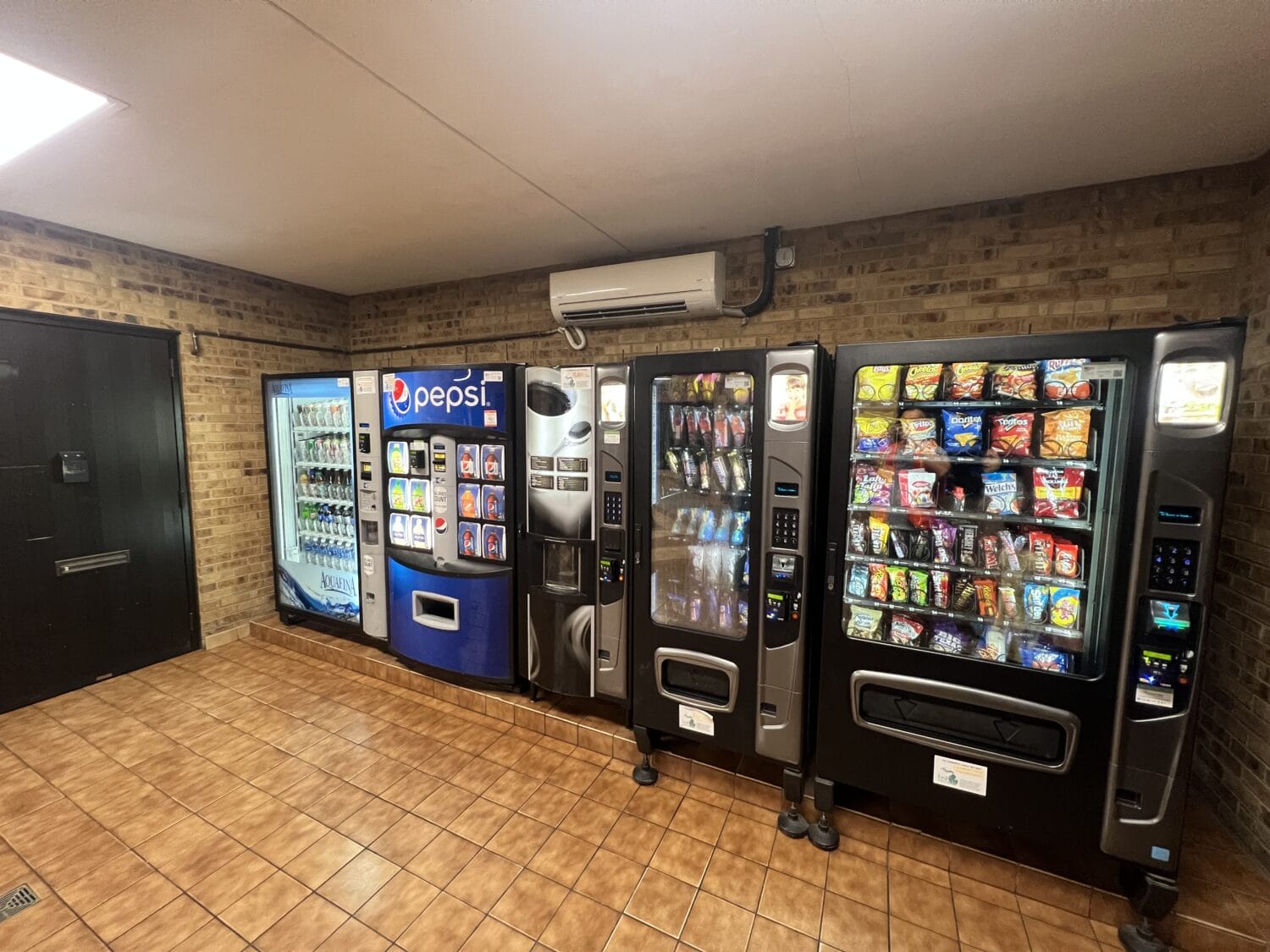 A snack area with vending machines offering various food and beverage options in a clean indoor setting.