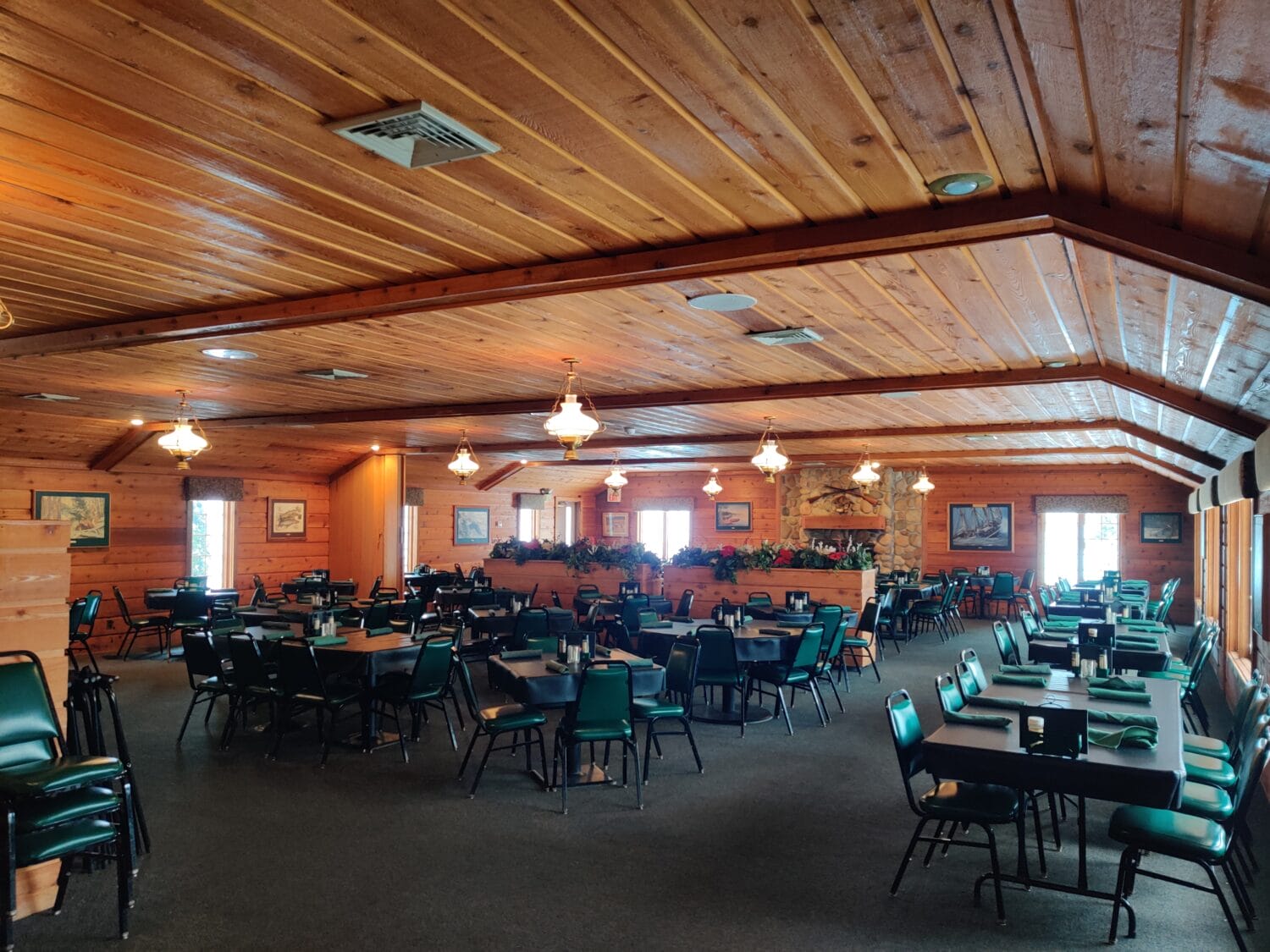 a spacious wood paneled dining room with green chairs and decorative lighting
