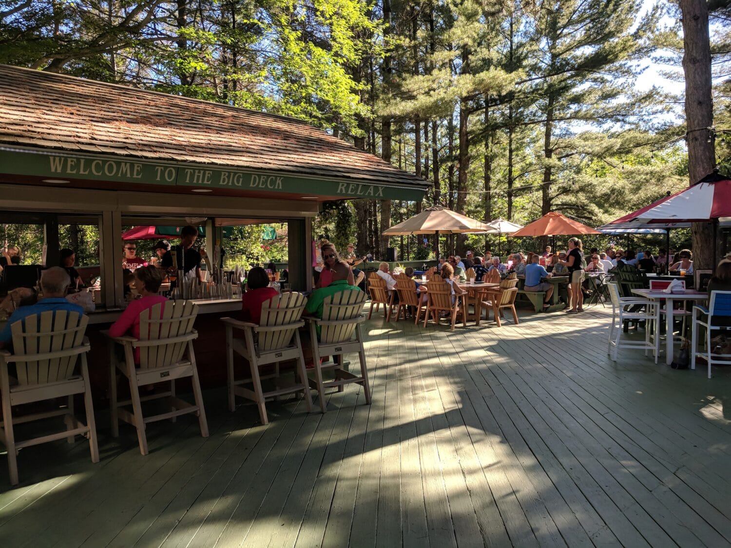 a sunny outdoor deck area at boones long lake inn with guests seated at picnic tables