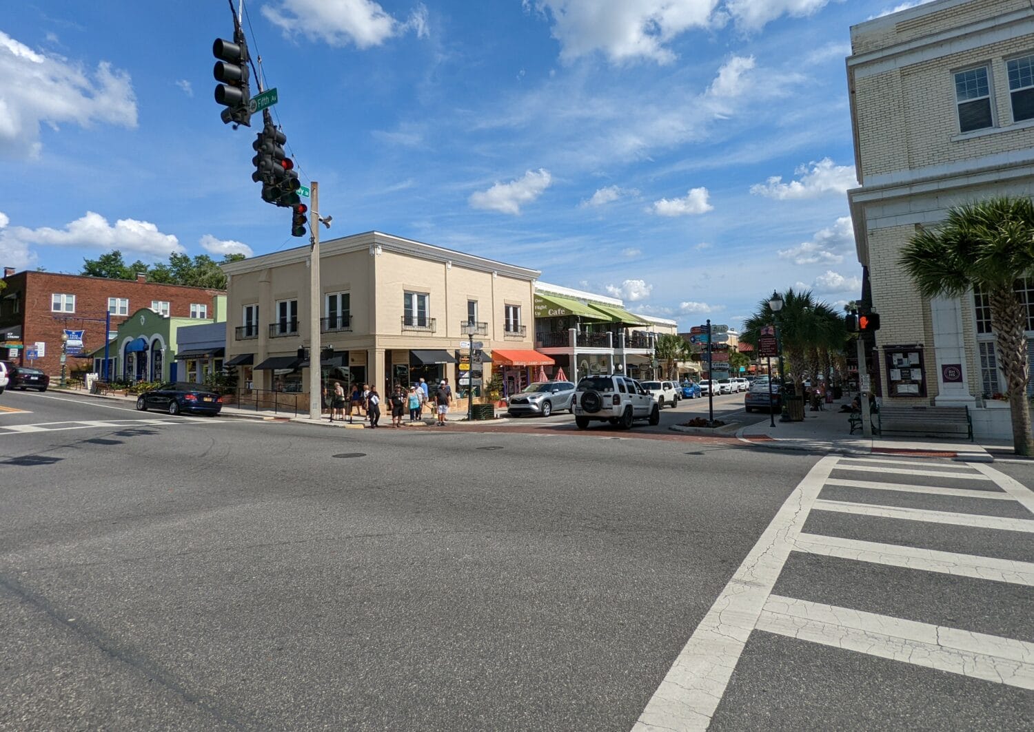 a sunny street corner in downtown mount dora with pedestrians classic architecture and bright blue skies