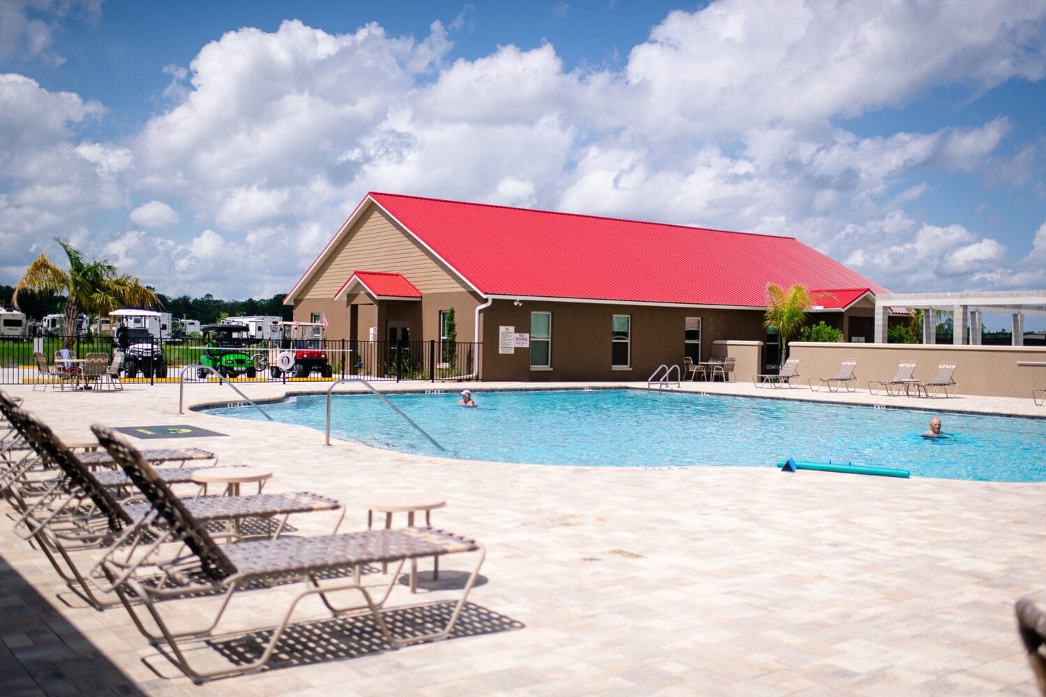 a swimming pool area with lounge chairs and a building in the background at keystone heights rv resort