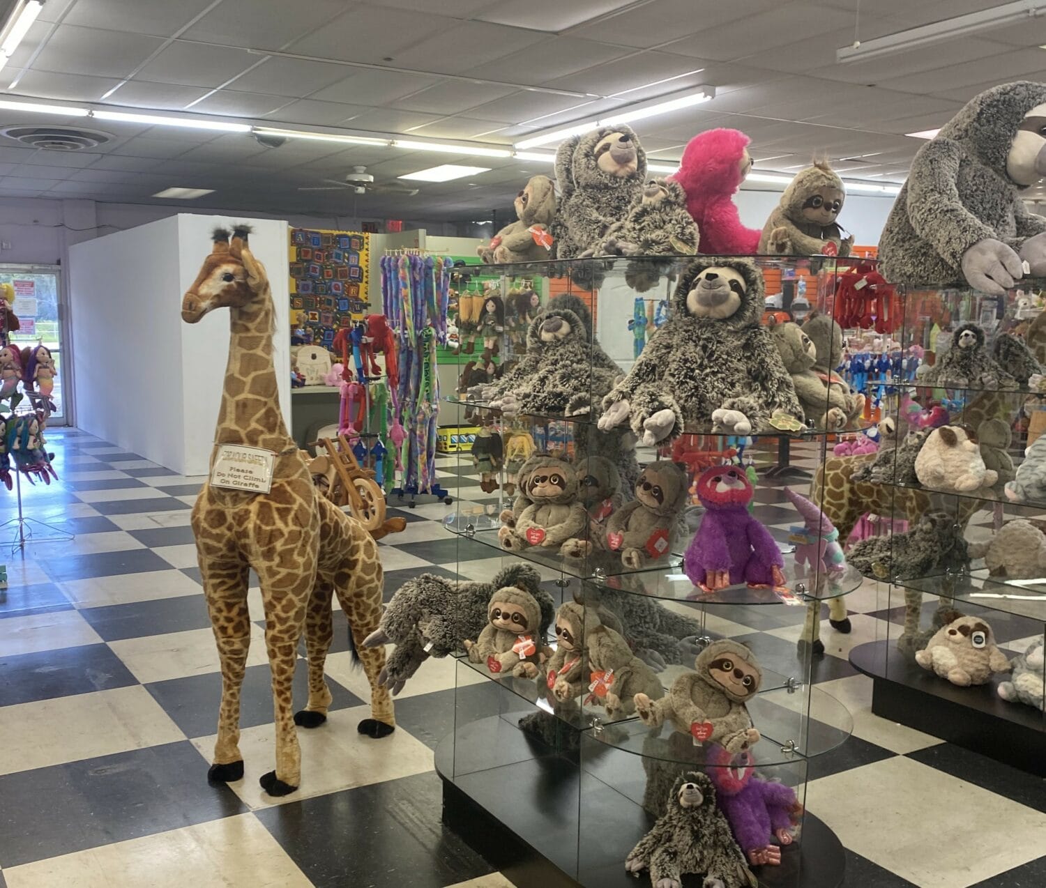 a variety of plush toys displayed in a gift shop with a tall giraffe plushie standing out amongst various stuffed animals