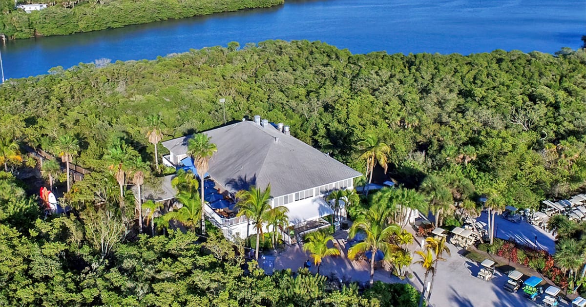 an aerial view of a secluded rum bay restaurant surrounded by lush greenery near tranquil waters