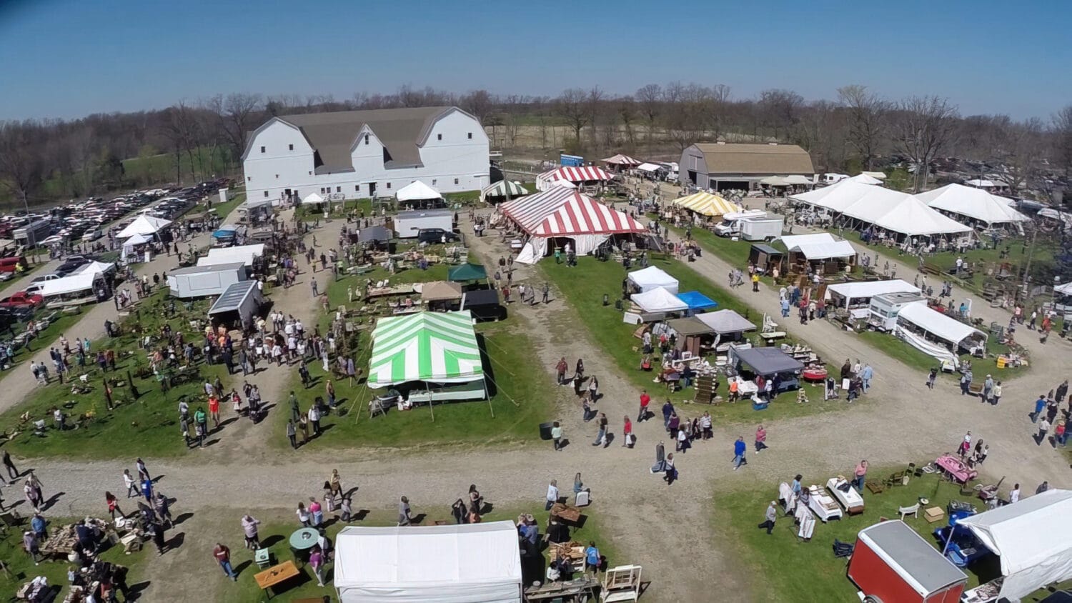 an aerial view of the michigan antique festival with white tents and crowds of people enjoying the sunny day