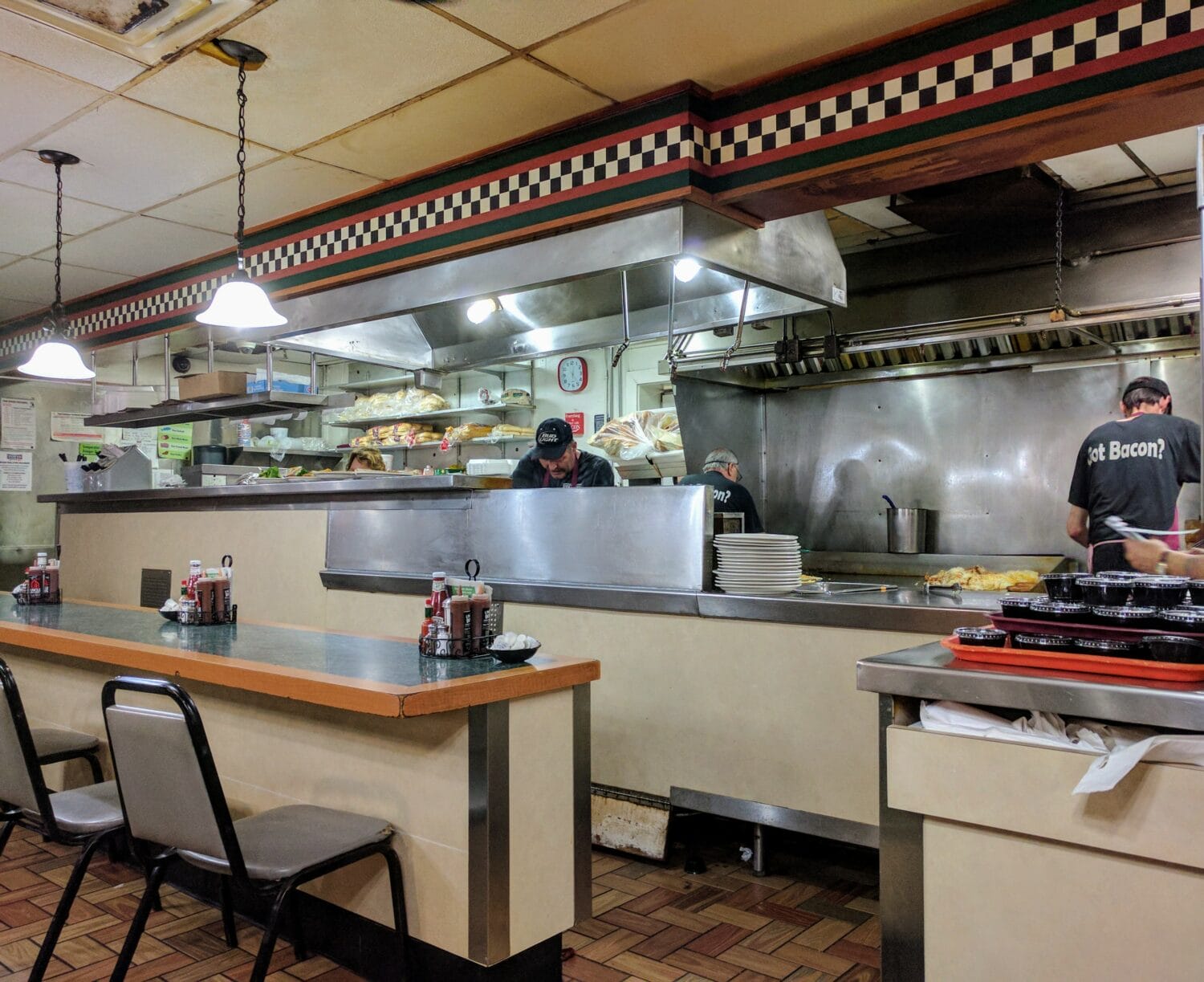 an image of a diners interior featuring a counter and kitchen area where chefs are preparing meals
