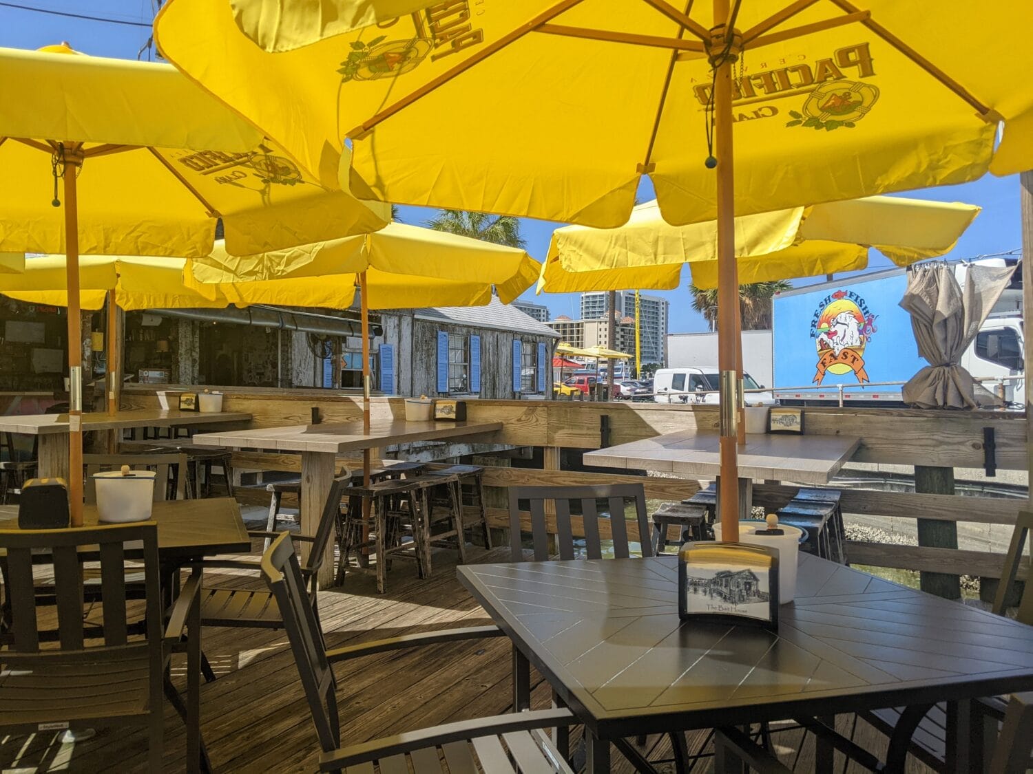 an outdoor dining area with yellow umbrellas and wooden tables offering a casual eating atmosphere in a sunny location