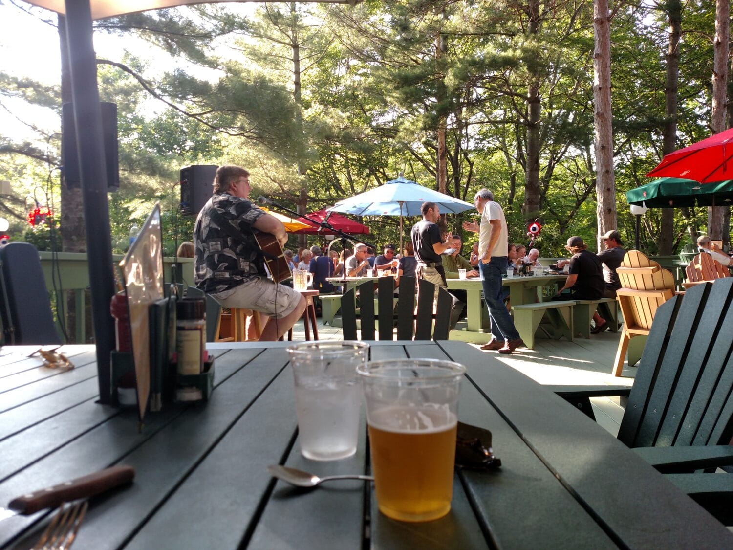 an outdoor patio dining scene with live music and patrons enjoying meals under umbrellas