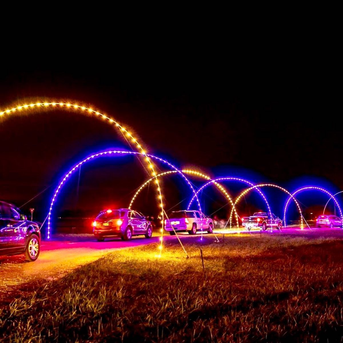 cars passing through a mile of dazzling arches of lights
