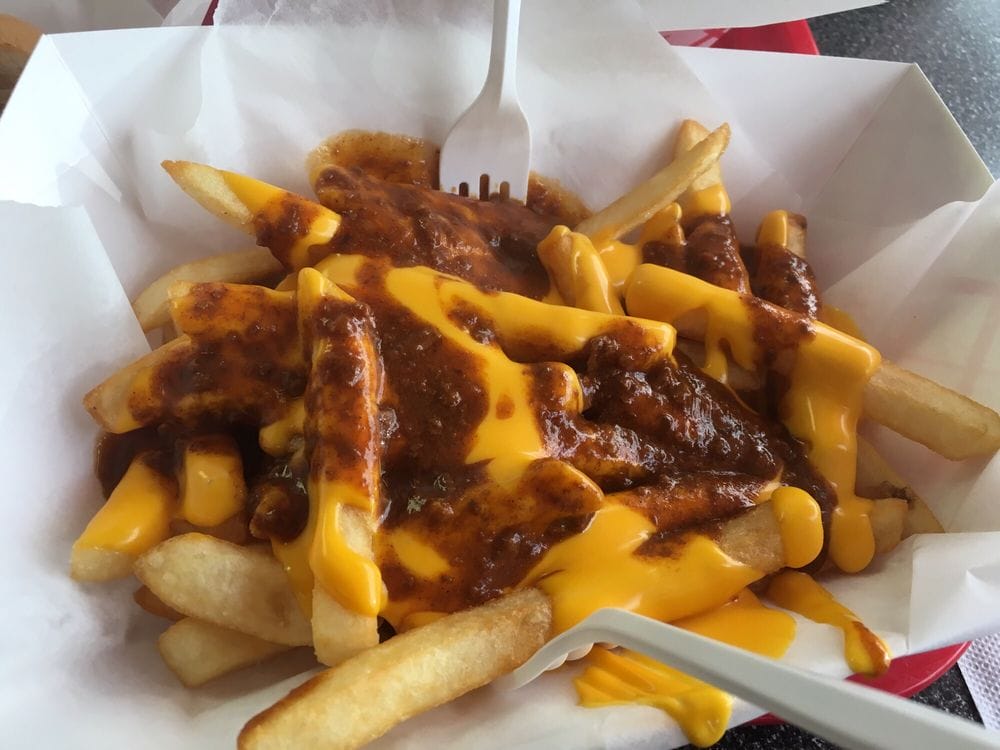 chili cheese fries in a paper tray with a plastic fork