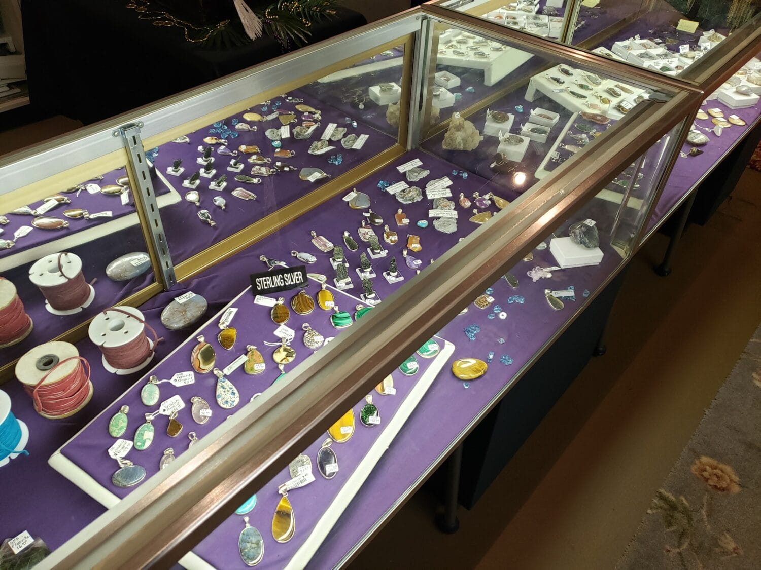 close up of a display case filled with various pieces of polished gemstone jewelry labeled as sterling silver