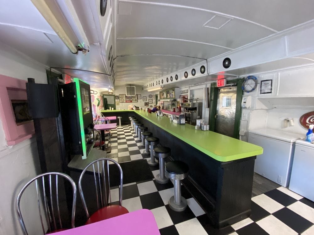 interior view of angels diner featuring a classic black and white checkered floor with pink and green accents and a vintage counter seating arrangement