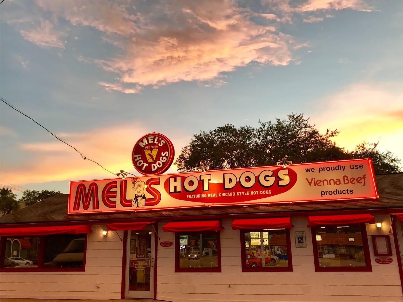 mels hot dogs sign illuminated at dusk with a beautiful sunset in the background