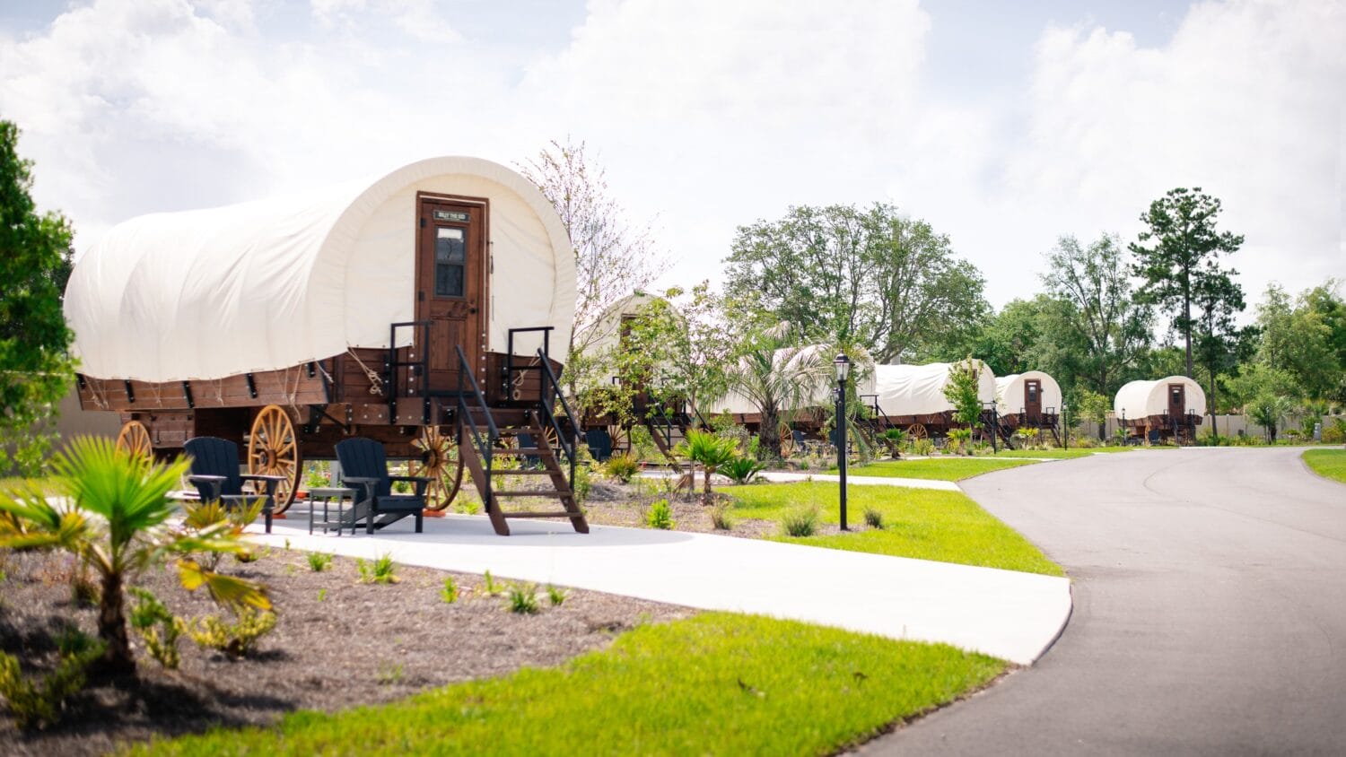 multiple covered wagons for lodging lined up along a curved path at keystone heights rv resort
