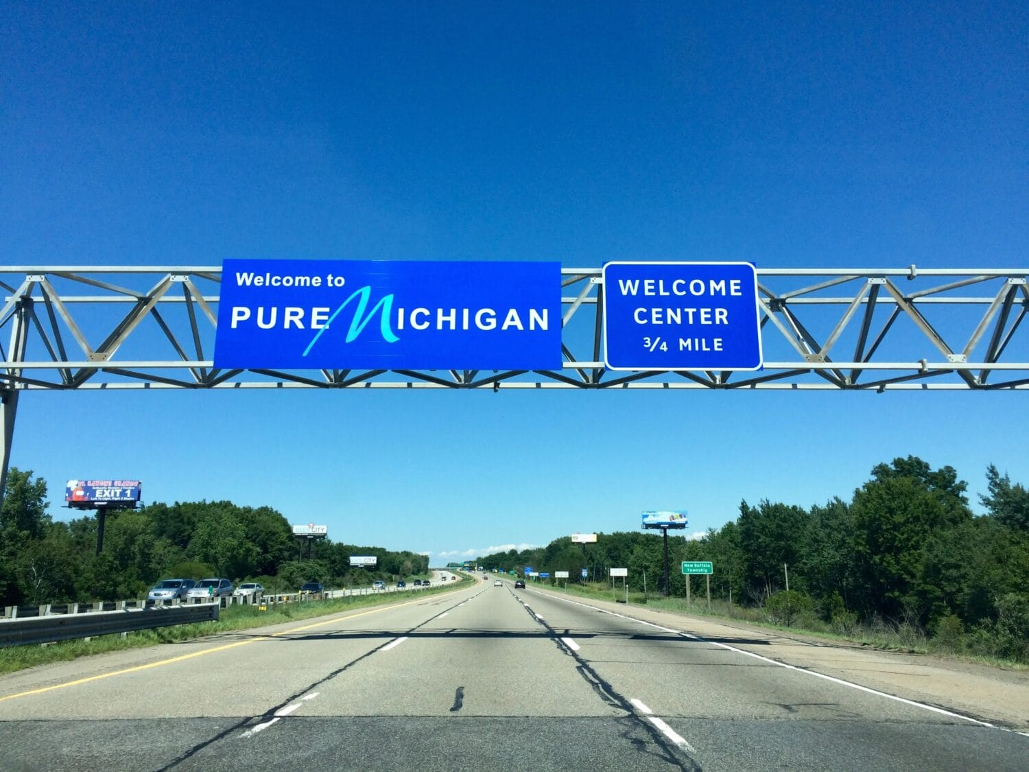 Overhead highway sign reading Welcome to PURE MICHIGAN with a WELCOME CENTER indicator.