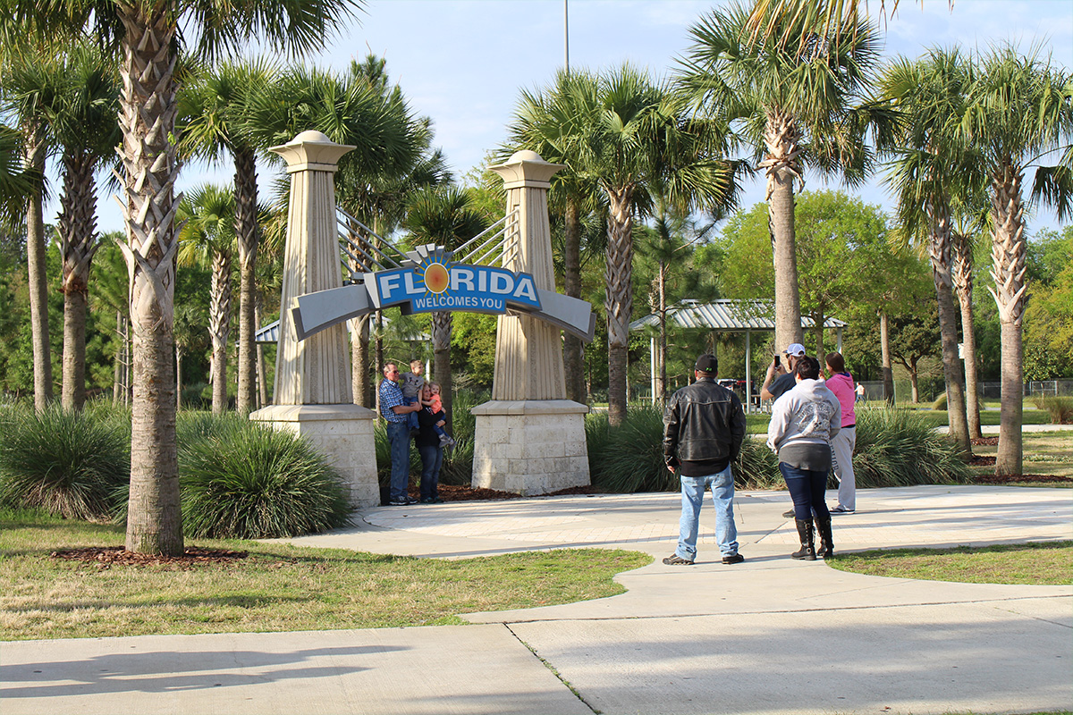 people taking pictures at the welcome sign