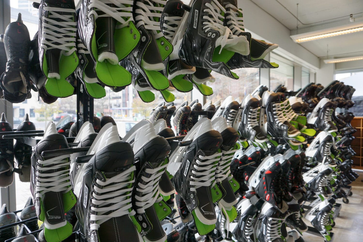 rows of ice skates with bright green accents are neatly arranged on racks for rent