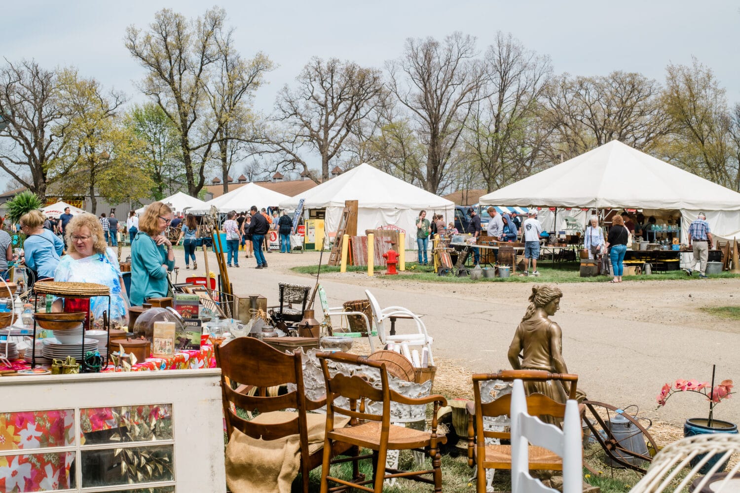 shoppers browse through a variety of stalls at the flea market with tents and vintage goods