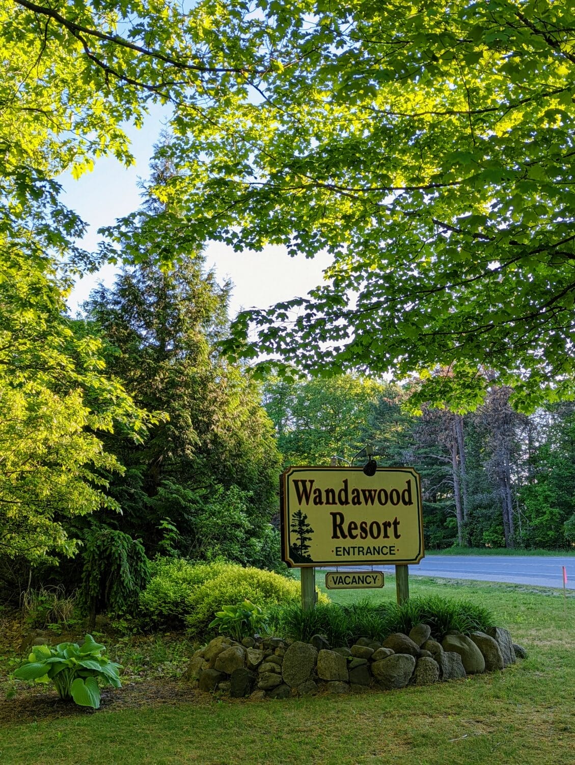 the entrance sign of wandawood resort surrounded by lush green foliage under a canopy of bright green leaves