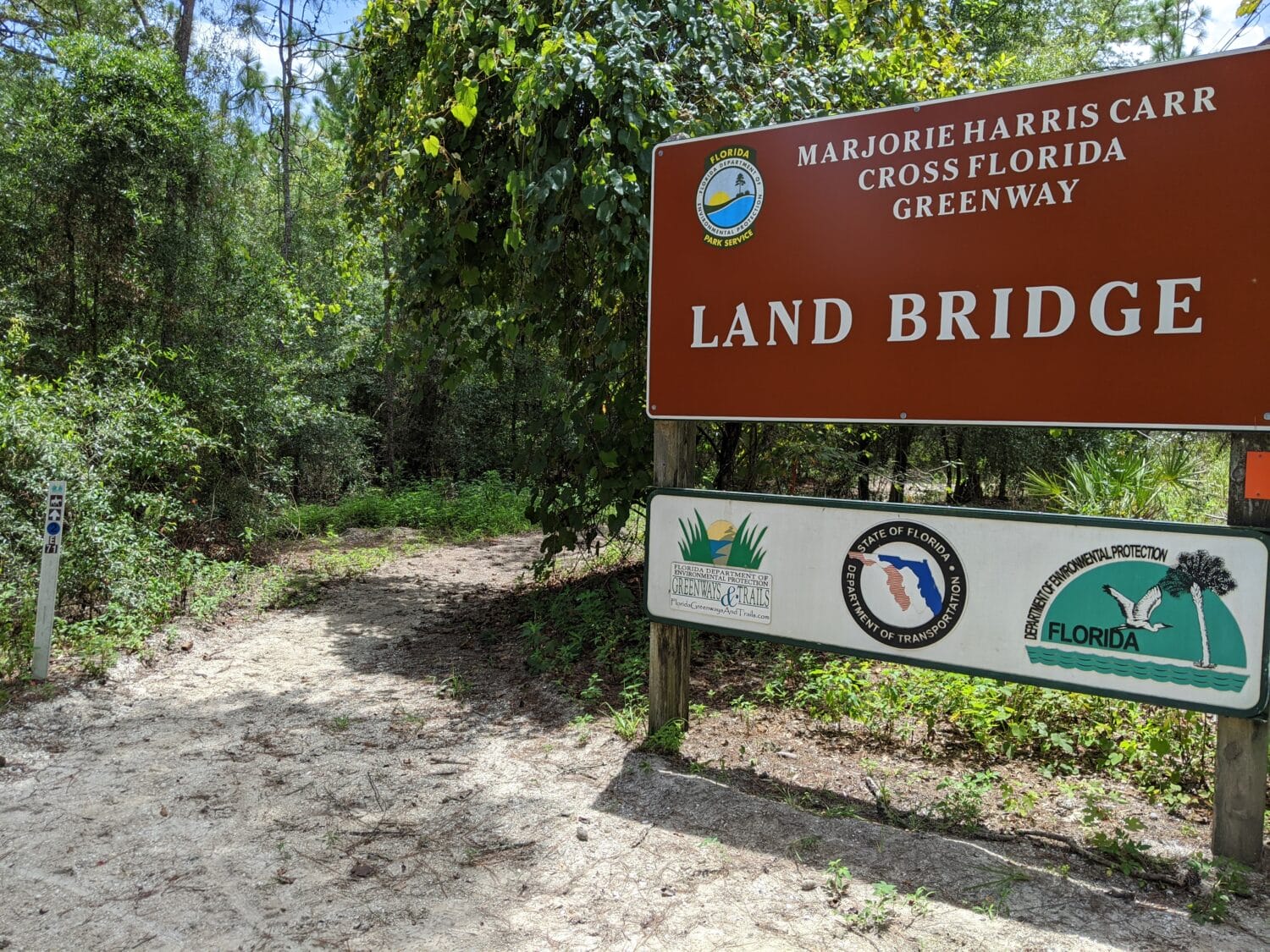 the entrance to the marjorie harris carr cross florida greenway land bridge with a trail leading into the woods