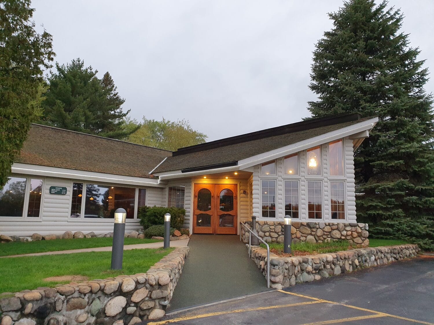 the exterior of boones long lake inn a cozy restaurant with large windows and a twilight sky