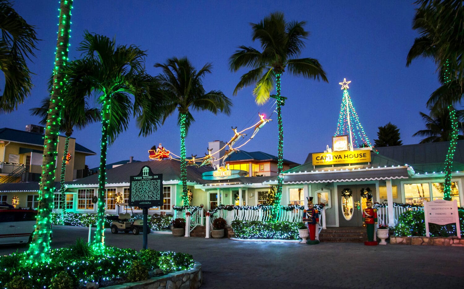 The exterior of Tween Waters Inn, fully decorated with holiday lights and decors