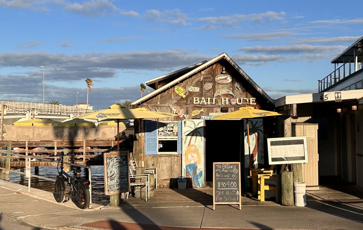the exterior of a beachside restaurant named bait house with a vintage look and surrounding tropical decor