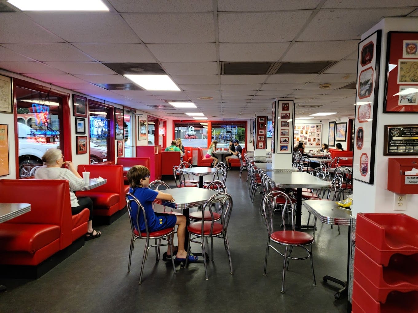 the interior of mels hot dogs with customers seated at tables and red booths