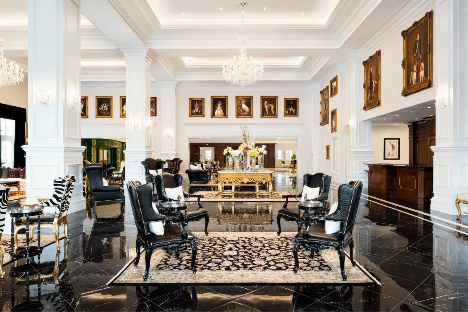 the lobby of the hotel with dark furnitire and hanging portraits