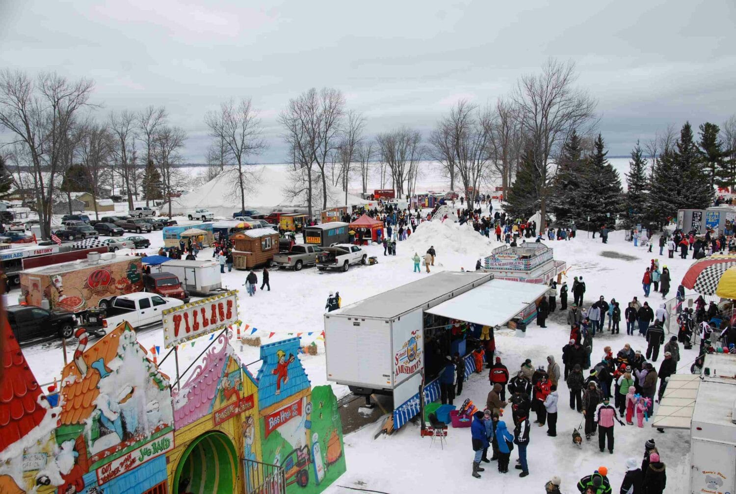 tip up town winter fair with a crowd of visitors amusement rides and colorful booths on snow covered ground