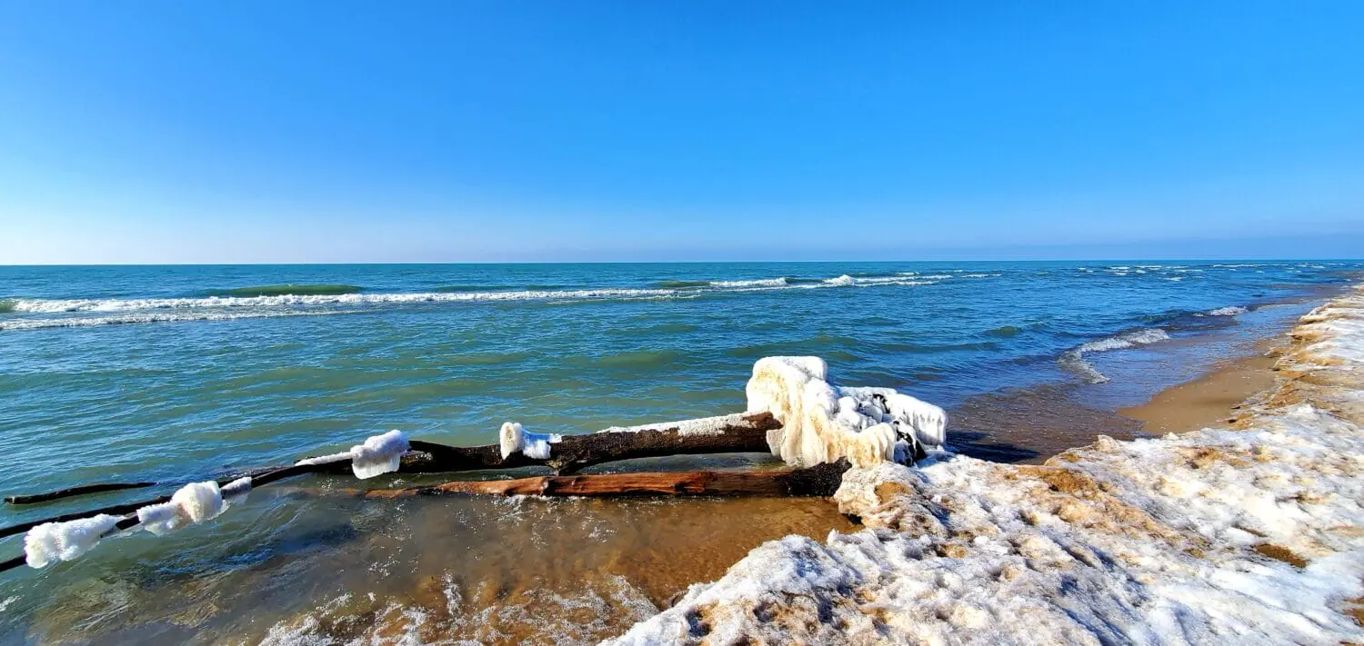 winters touch at the state park with icy formations adorning driftwood and a snowy beach meeting the waves